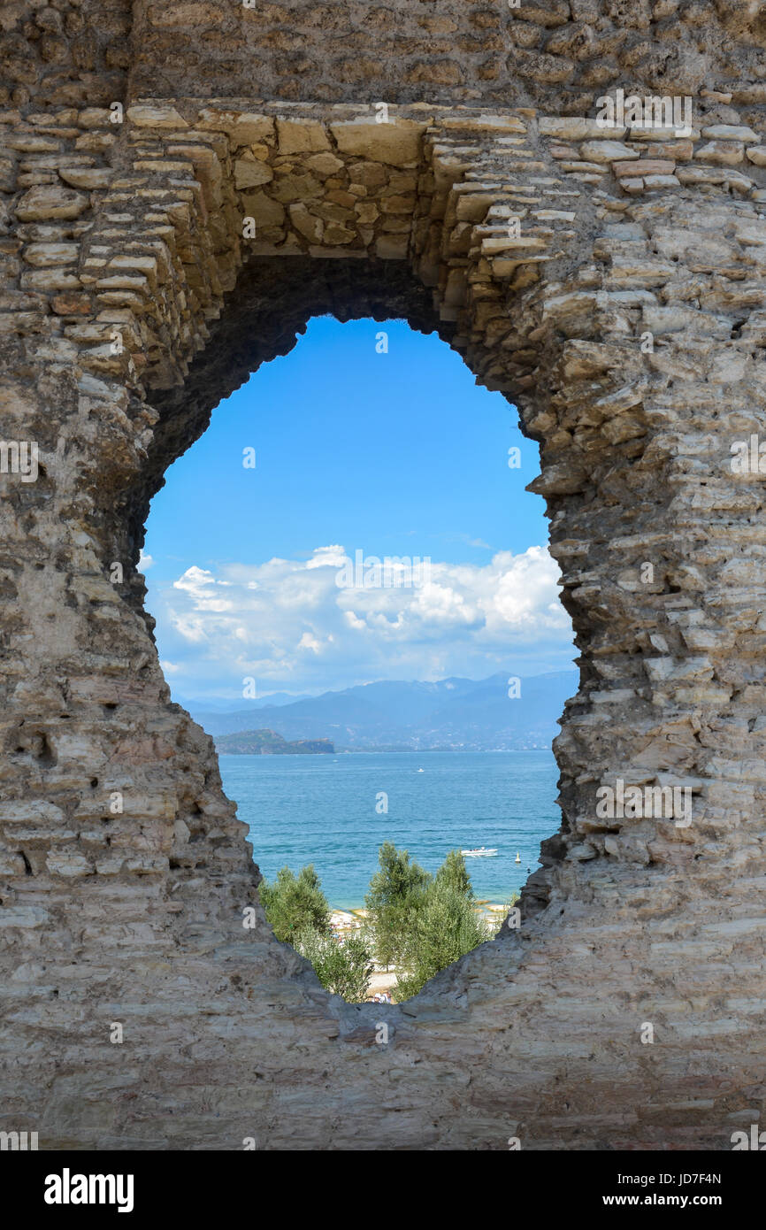 A hole in the wall of the Grotto di Catullo is like a portal with a ...