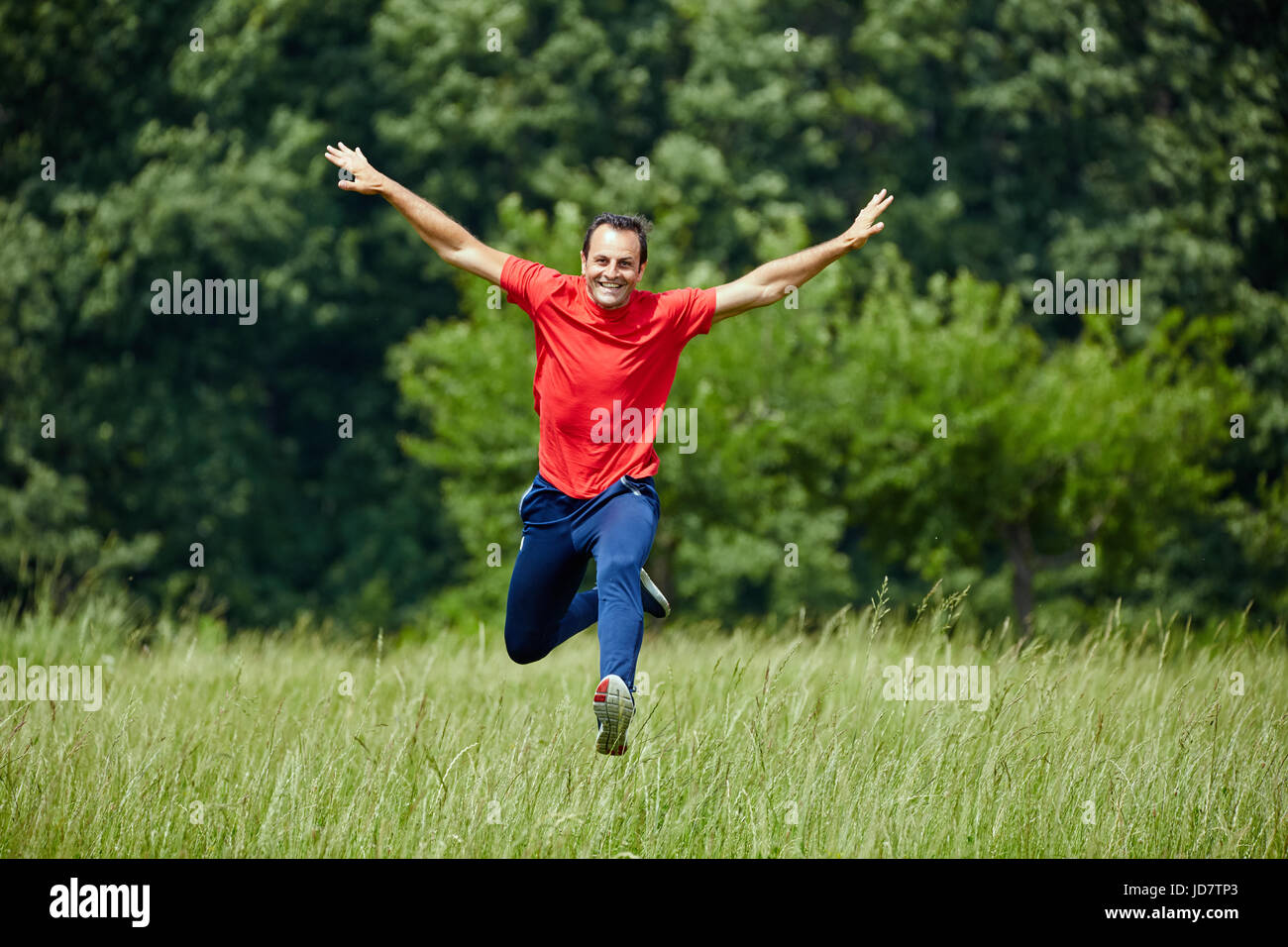 Man jogging and jumping for joy by the forest Stock Photo - Alamy
