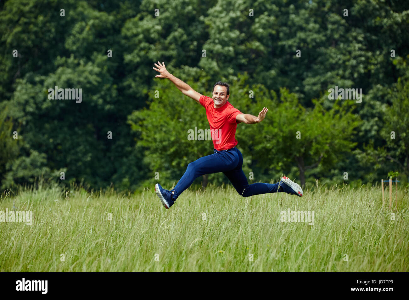 Man jogging and jumping for joy by the forest Stock Photo - Alamy