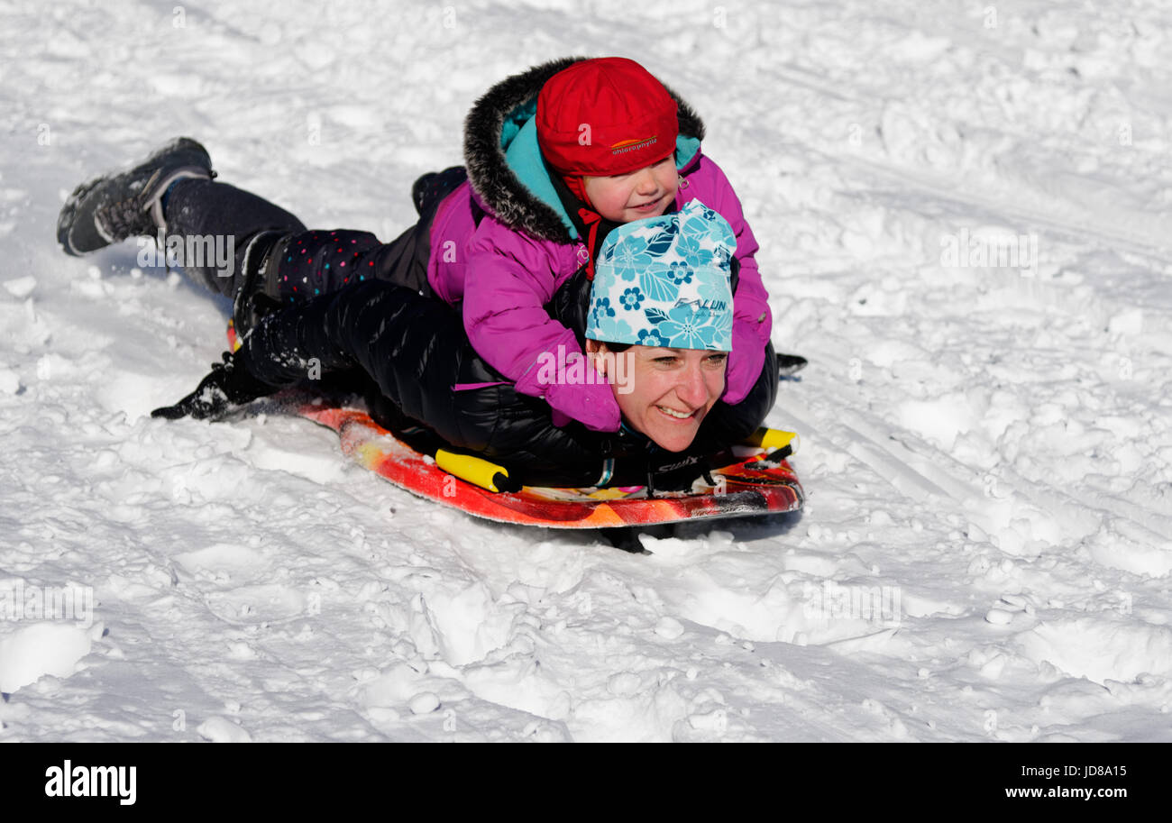 A young child riding on the back of an adult on a sledge Stock Photo ...
