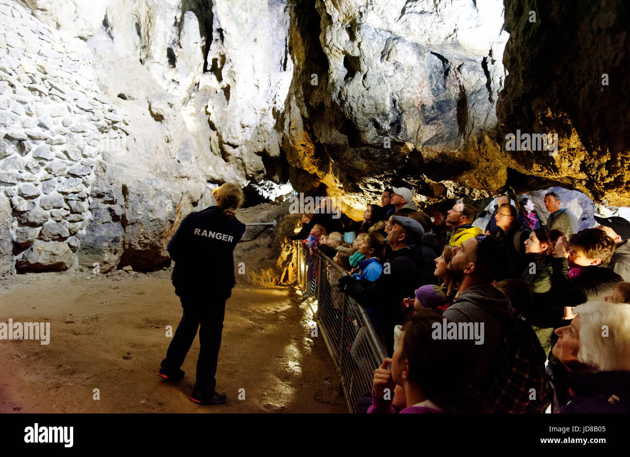 A guide showing people rock formations in Great Masson Cavern at ...