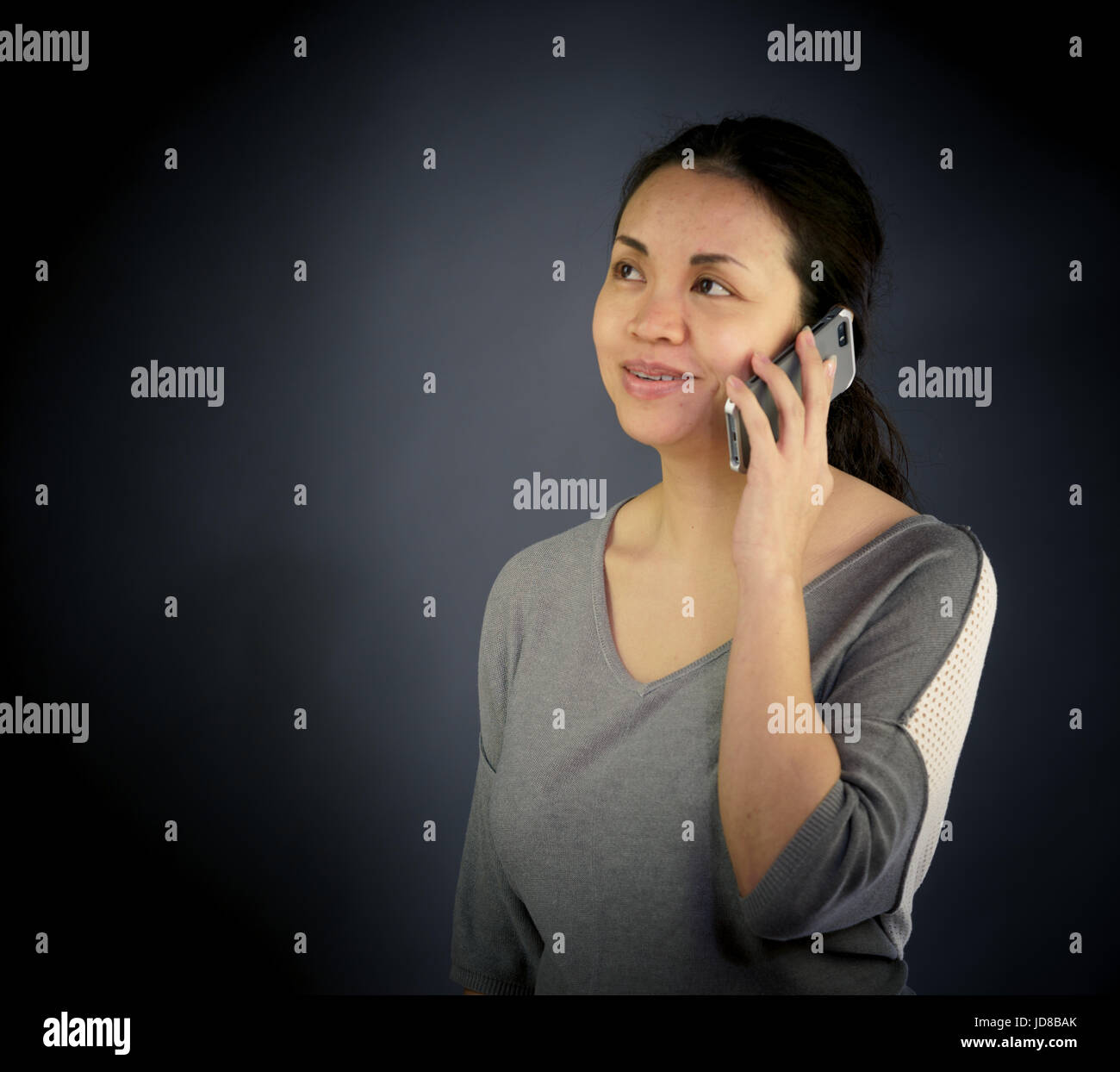 Portrait of woman using mobile phone, studio shot, plain background ...