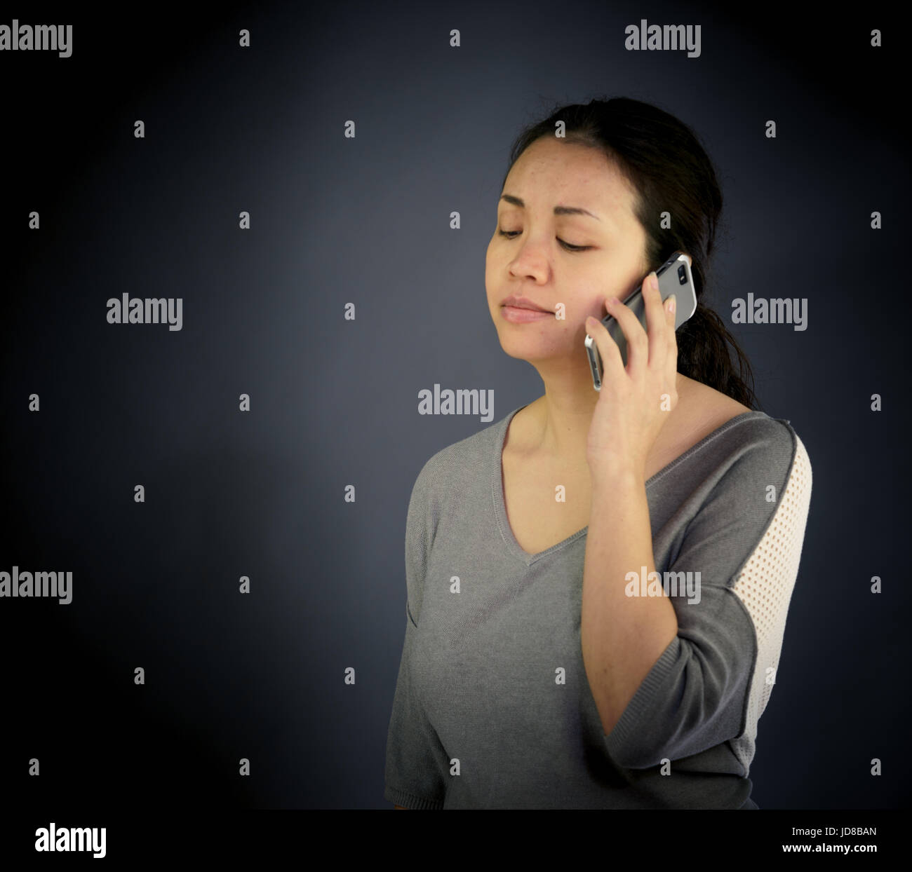 Portrait of woman using mobile phone, studio shot, plain background ...