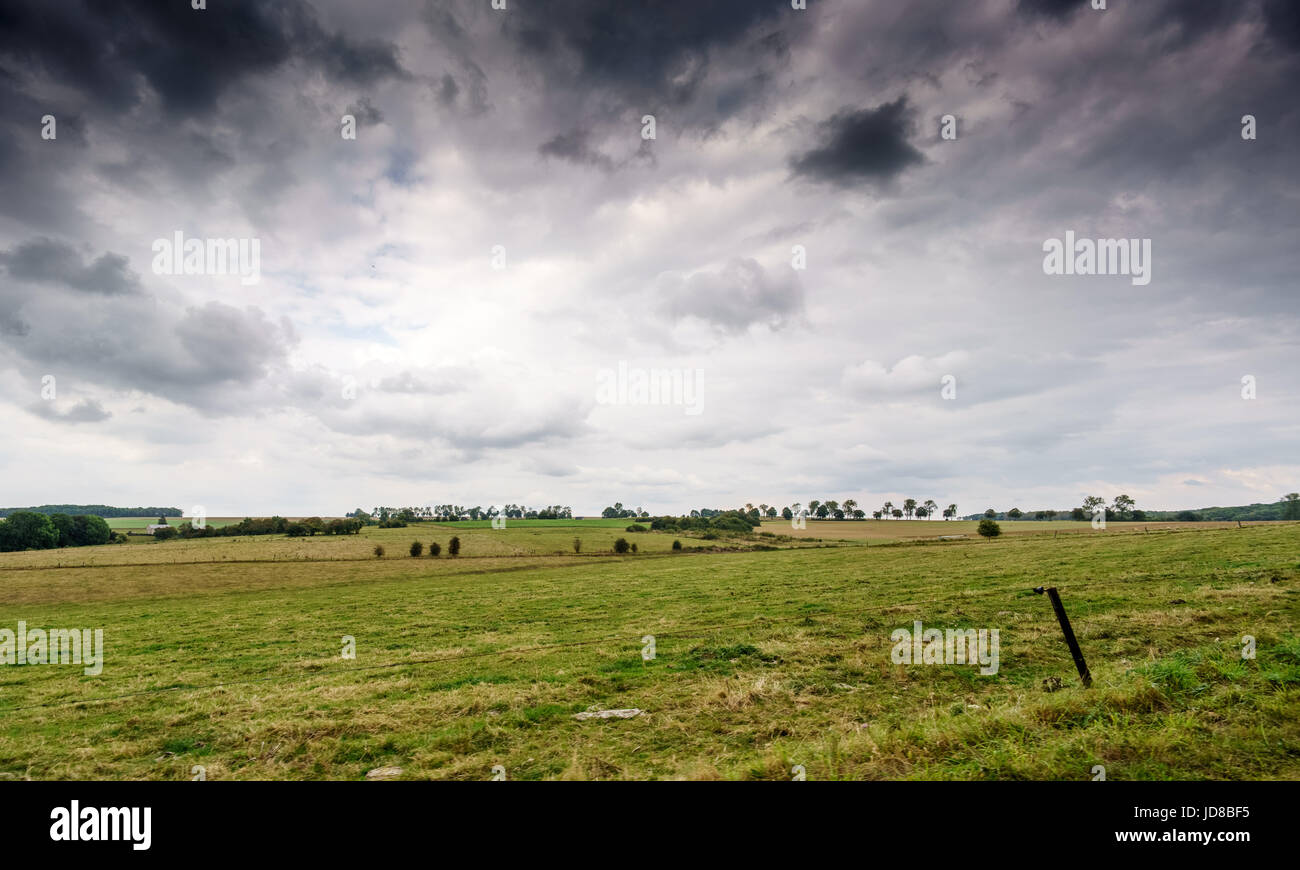 Sparse rural green field in countryside against cloudy sky, Belgium ...