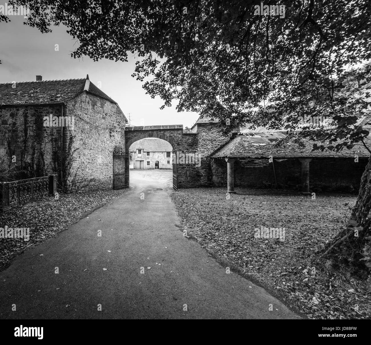 Old stone rustic building with archway and tree in foreground hi-res ...