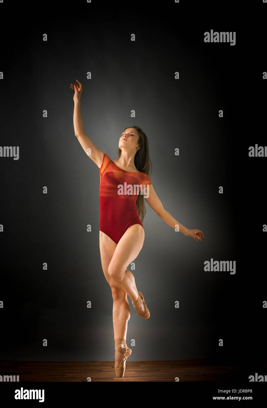 Female ballet dancer on one leg with arms stretched out, studio shot ...