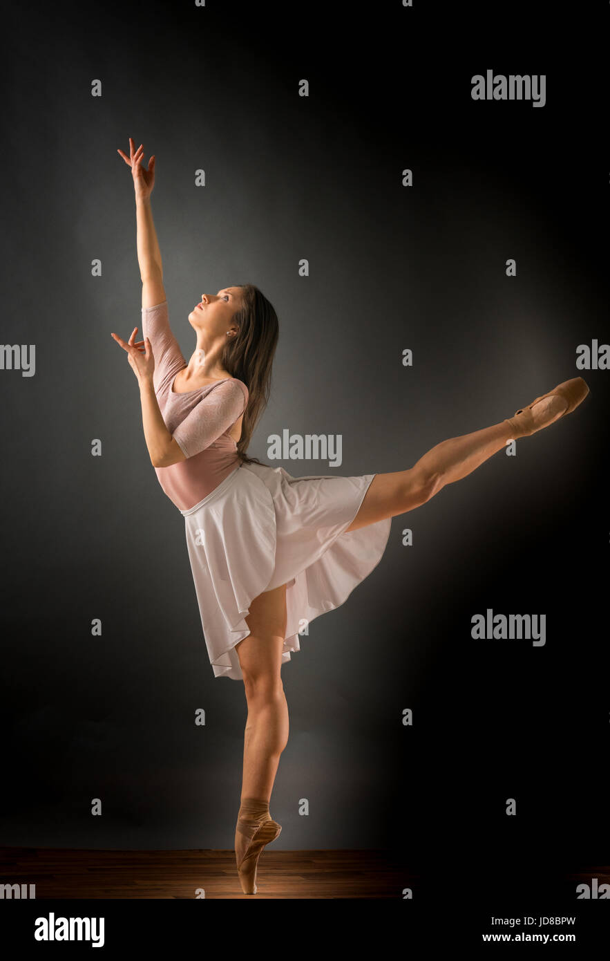Female ballet dancer on one leg with arms stretched up, studio shot ...