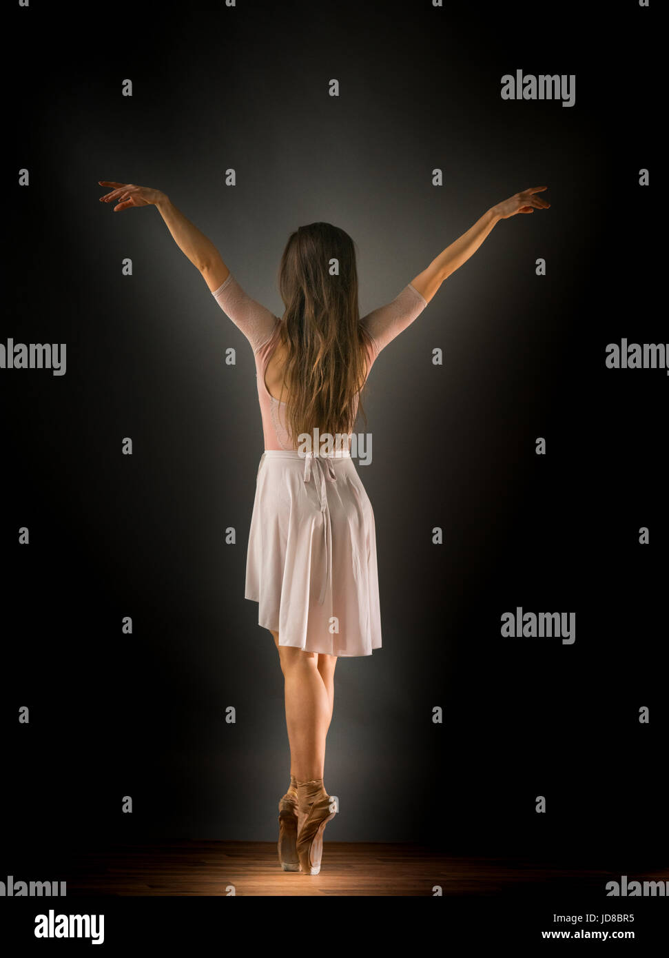 Female ballet dancer on pointe with arms stretched up, studio shot ...