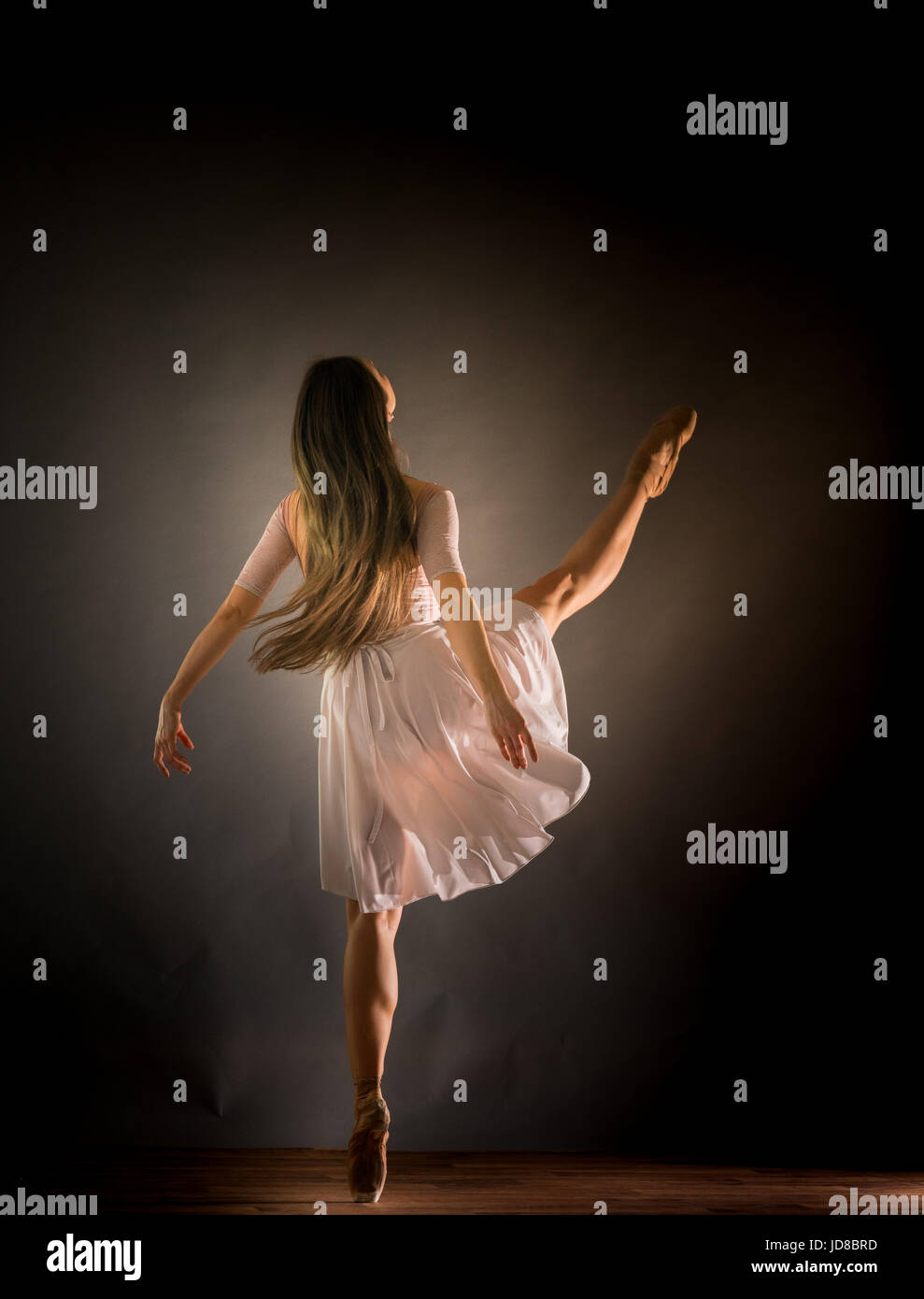 Female ballet dancer on one leg with arms behind, studio shot ...