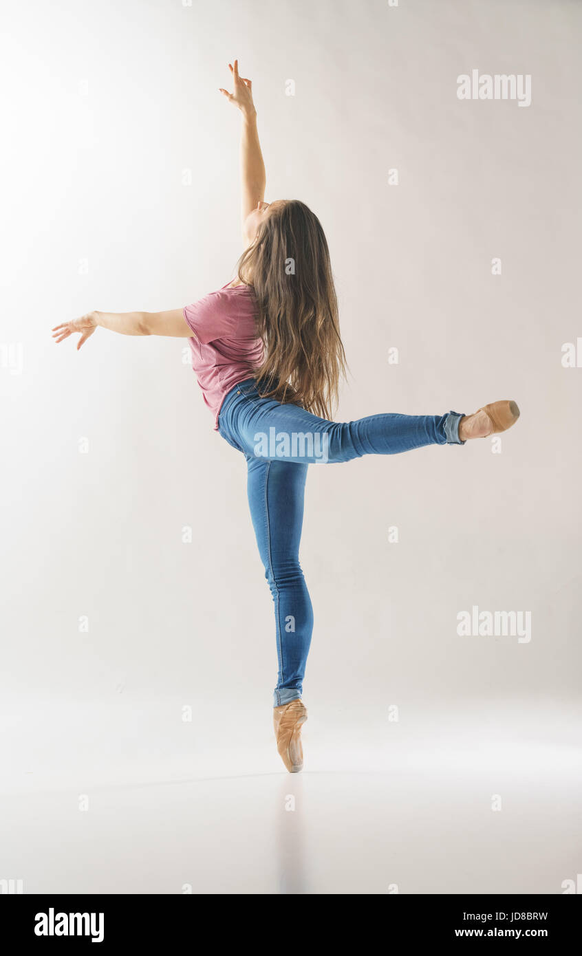 Female ballet dancer on one leg, wearing casual clothing, studio shot ...