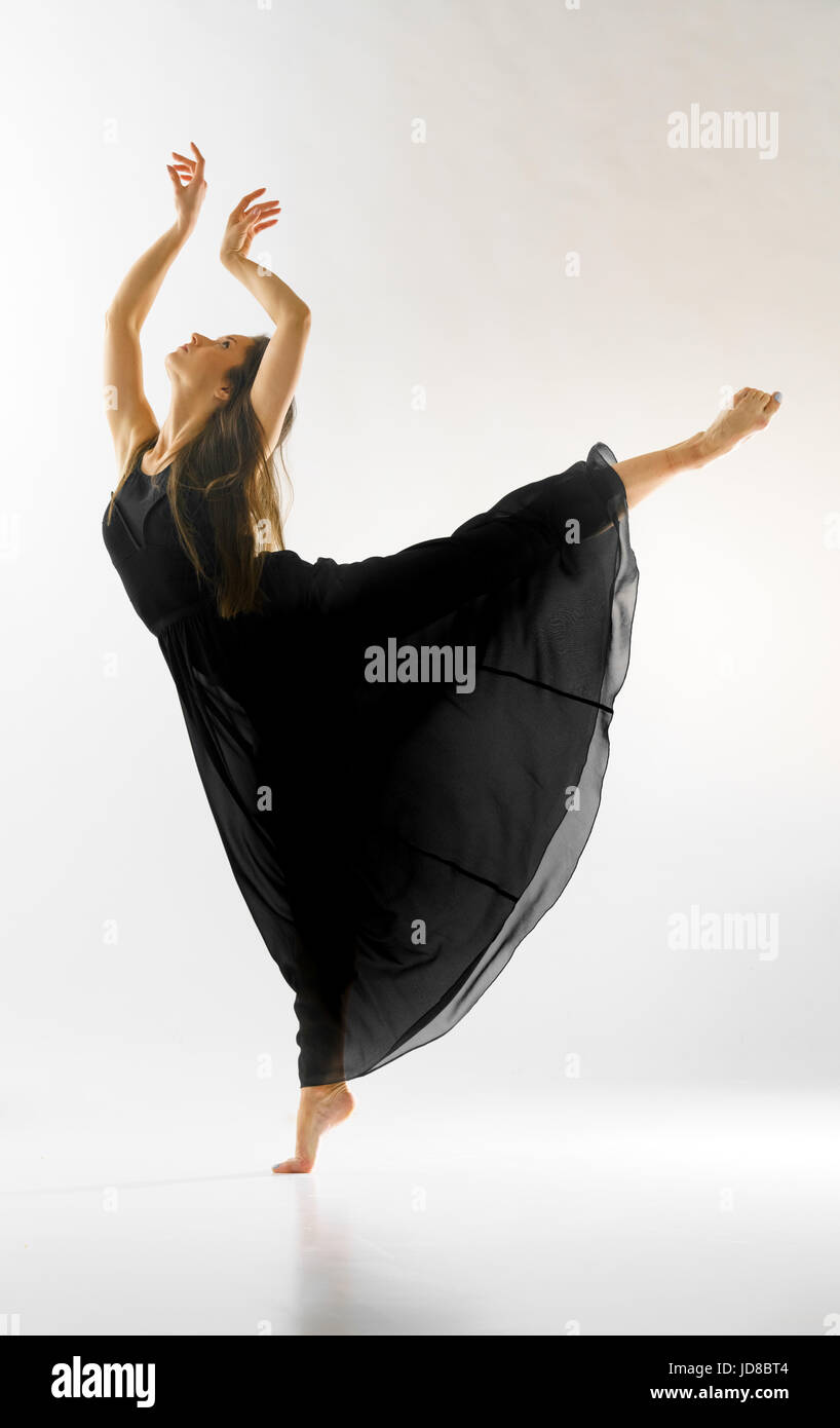 Female ballet dancer on one leg with arms lifted above, studio shot ...