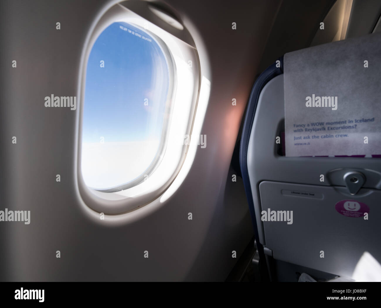 Looking through aircraft window at wing, clouds and blue sky. Iceland ...