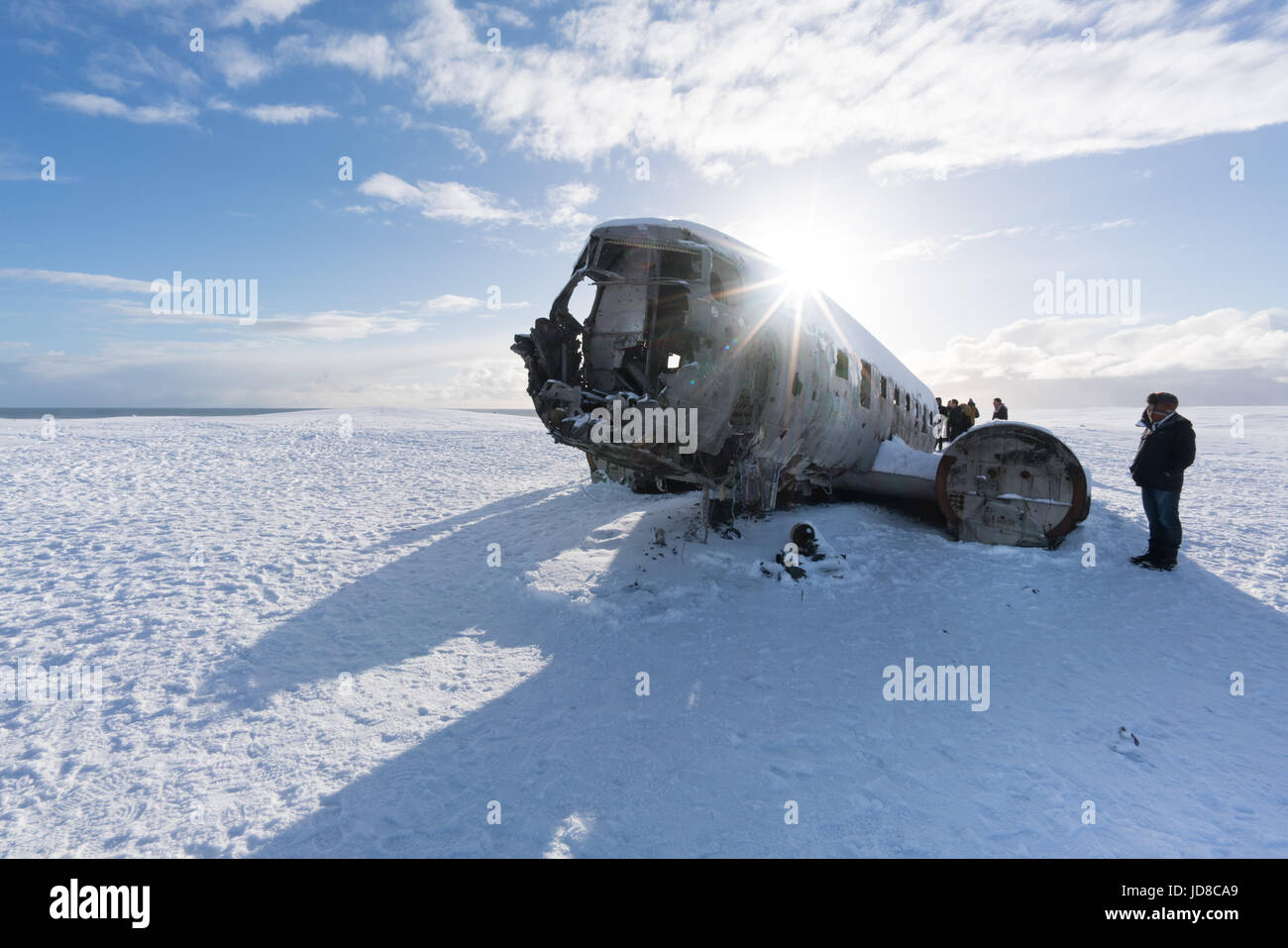 Two people standing by helicopter wreck on snow covered landscape ...