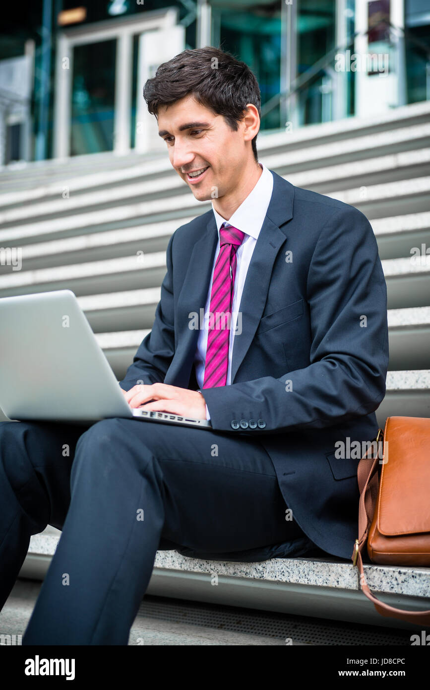 Young businessman using a laptop with wireless internet connection ...