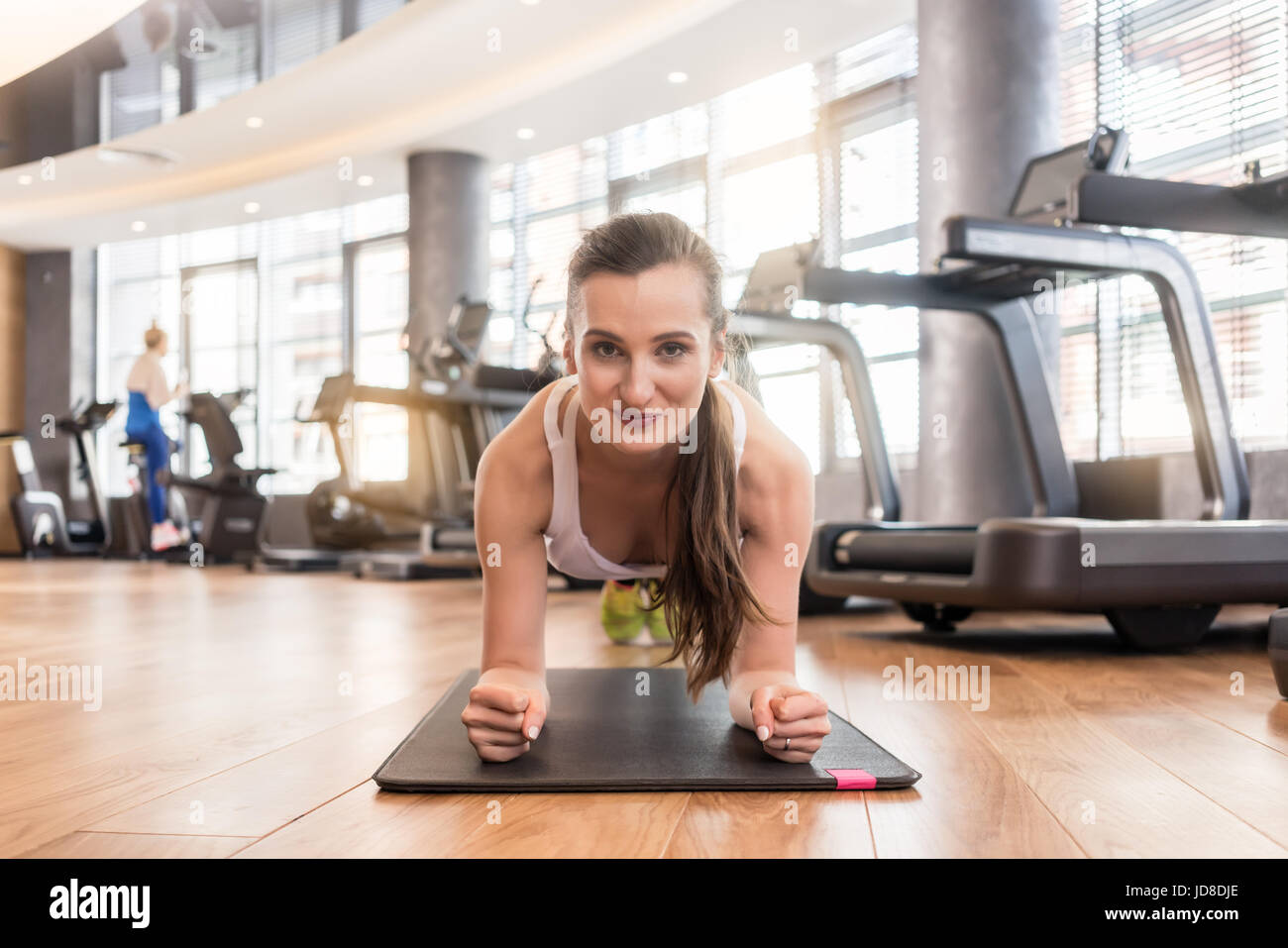 Front view of a young fit woman smiling while practicing the forearm ...