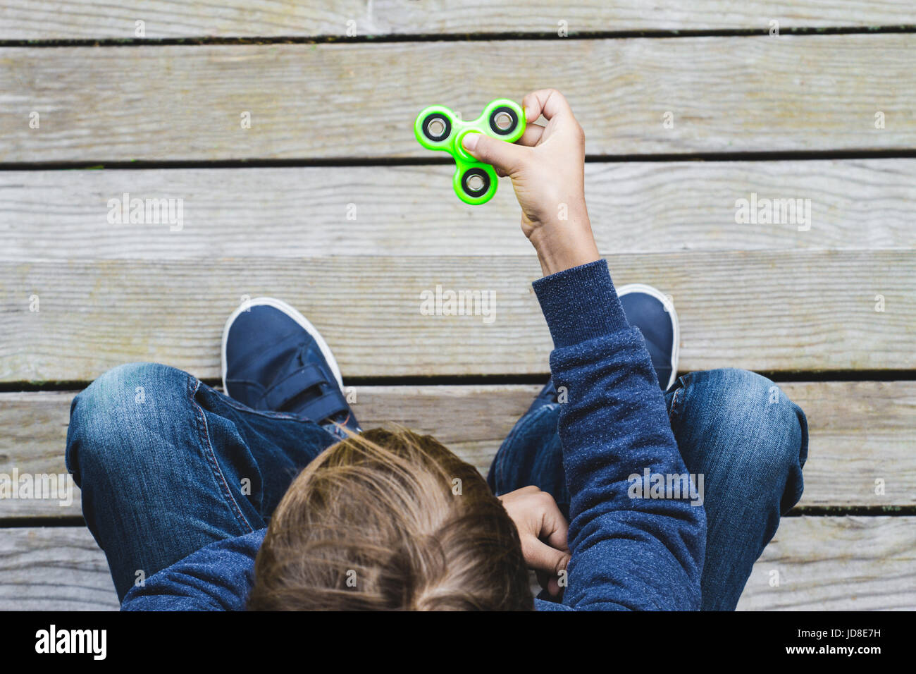 Child playing with fidget spinner outdoors. Top view Stock Photo - Alamy