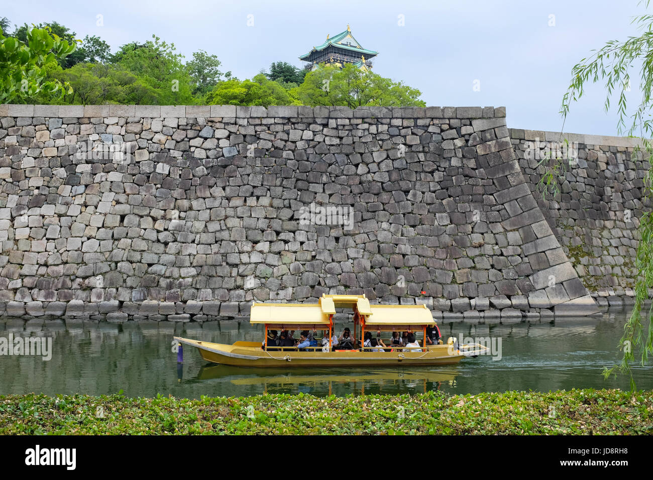 A boat taking tourists on a trip on the moat of Osaka Caslte in the ...