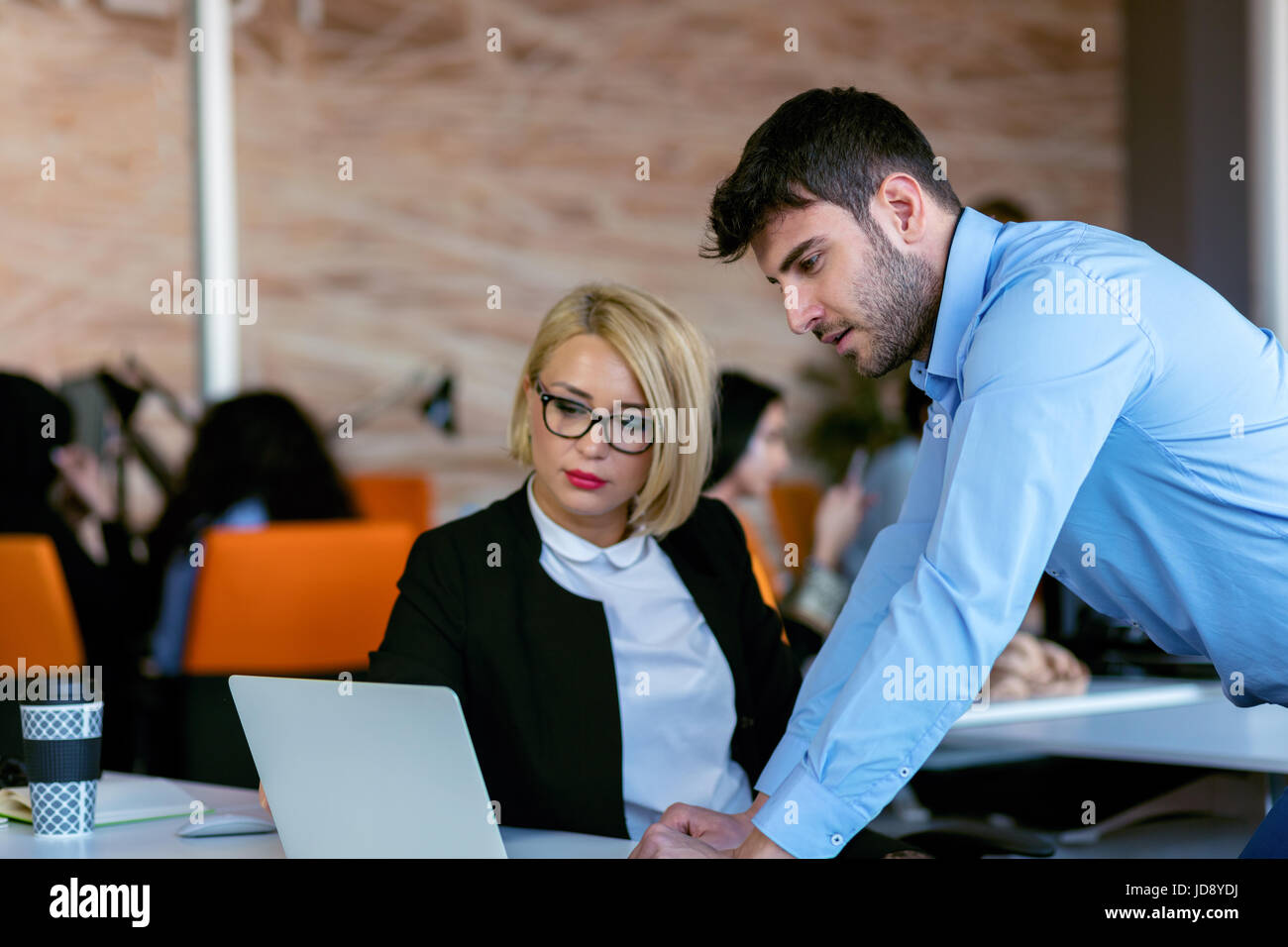 Colleagues chatting, sitting together at office table, smiling Stock ...