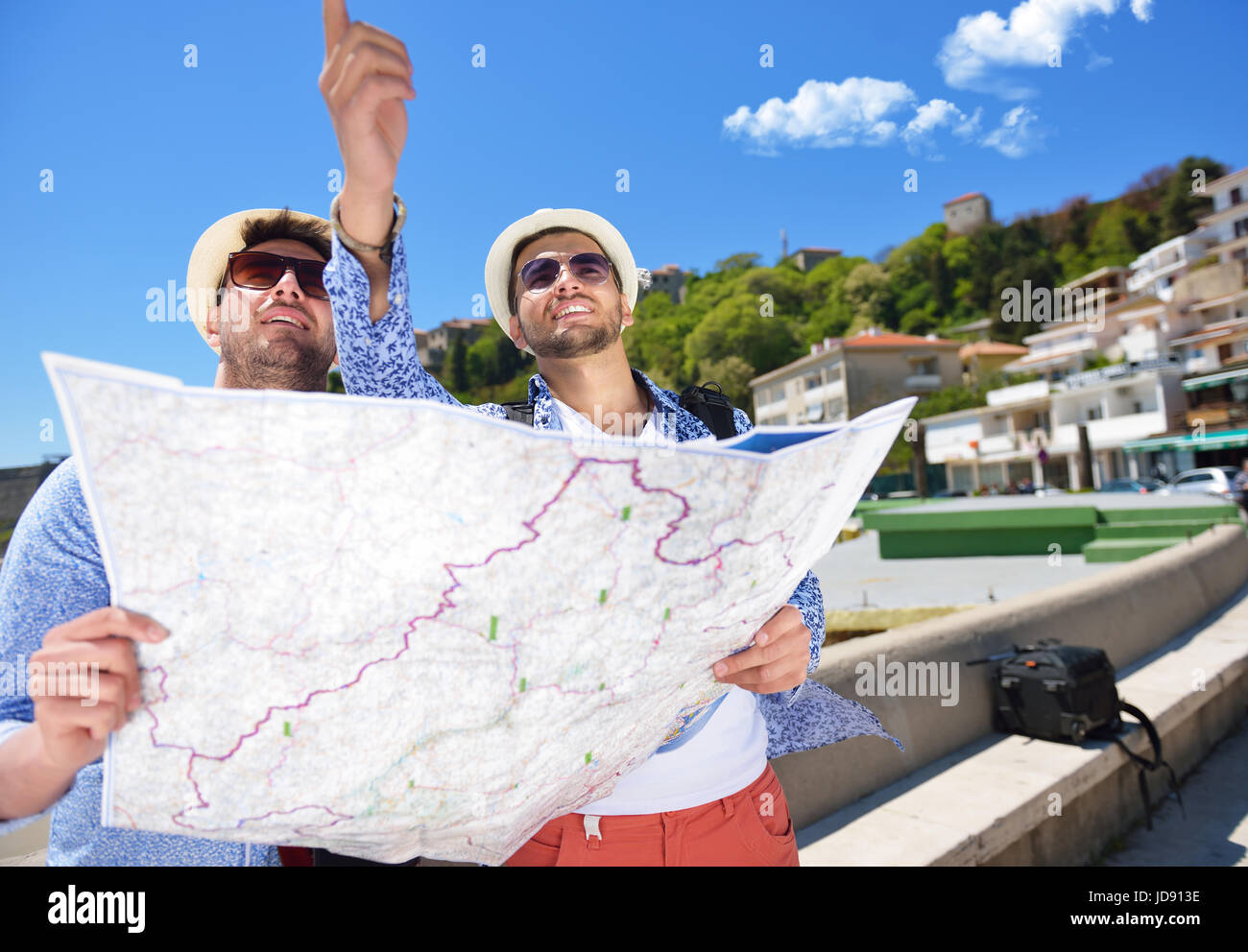 Portrait of a smiling tourist with map and bag Stock Photo - Alamy