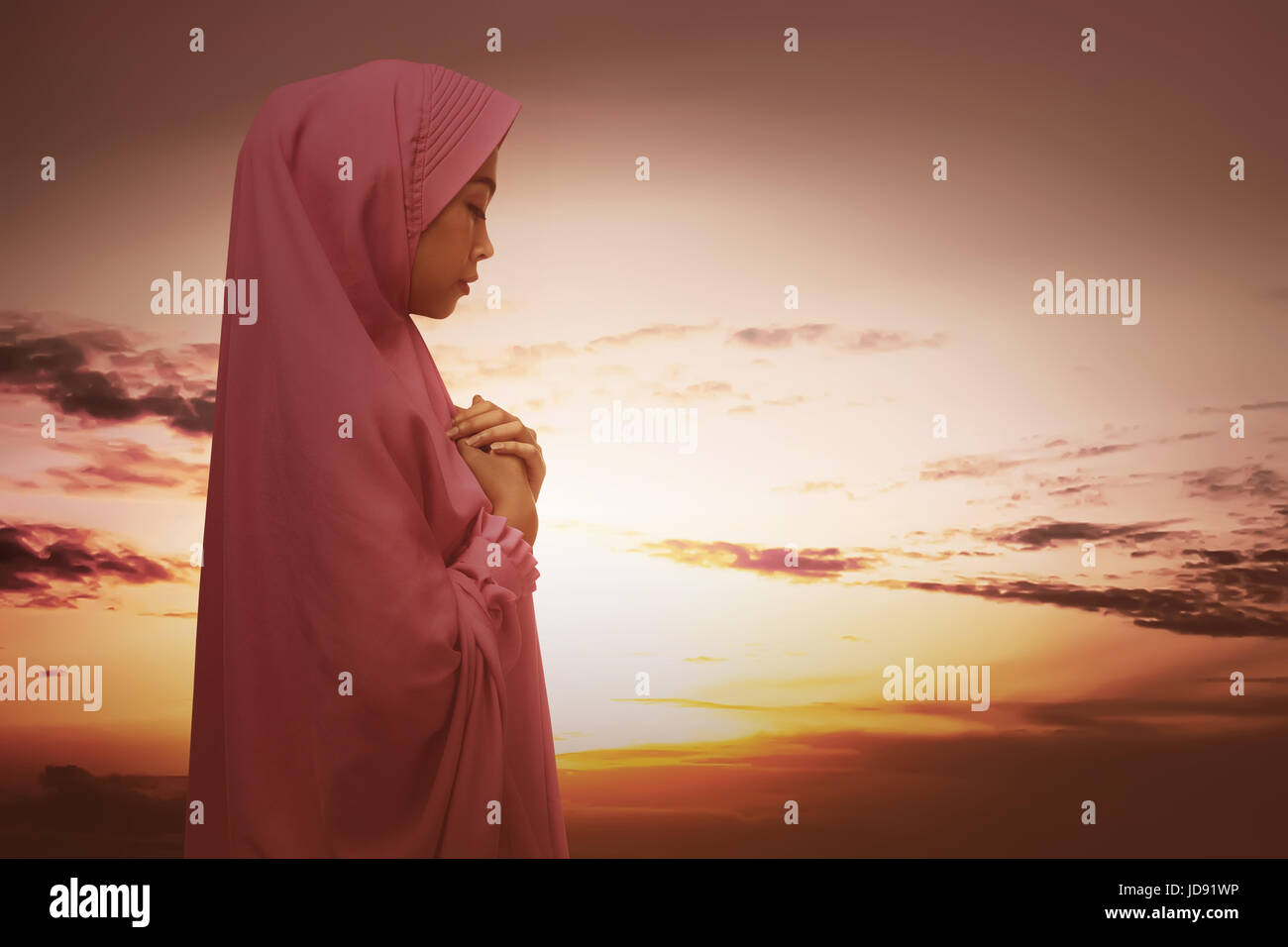 Beautiful asian muslim woman with hijab praying against sunset at sky ...