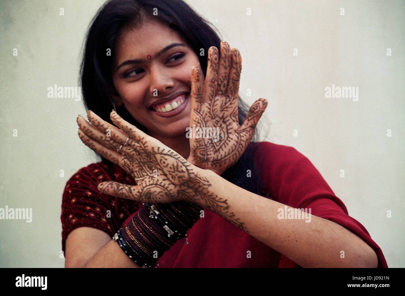 smilling face of a young girl after painting her hand with mehedi ...