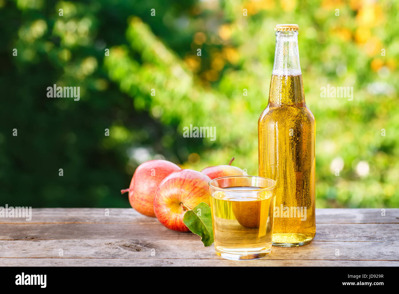 apple cider in glass and bottle on wooden table on blurred natural ...