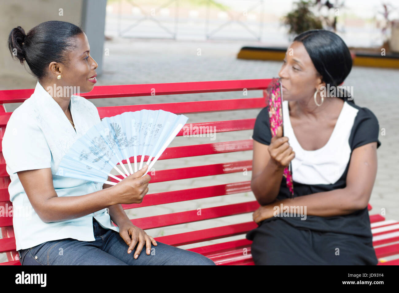 two young women sitting on a bench are talking and listen carefully ...