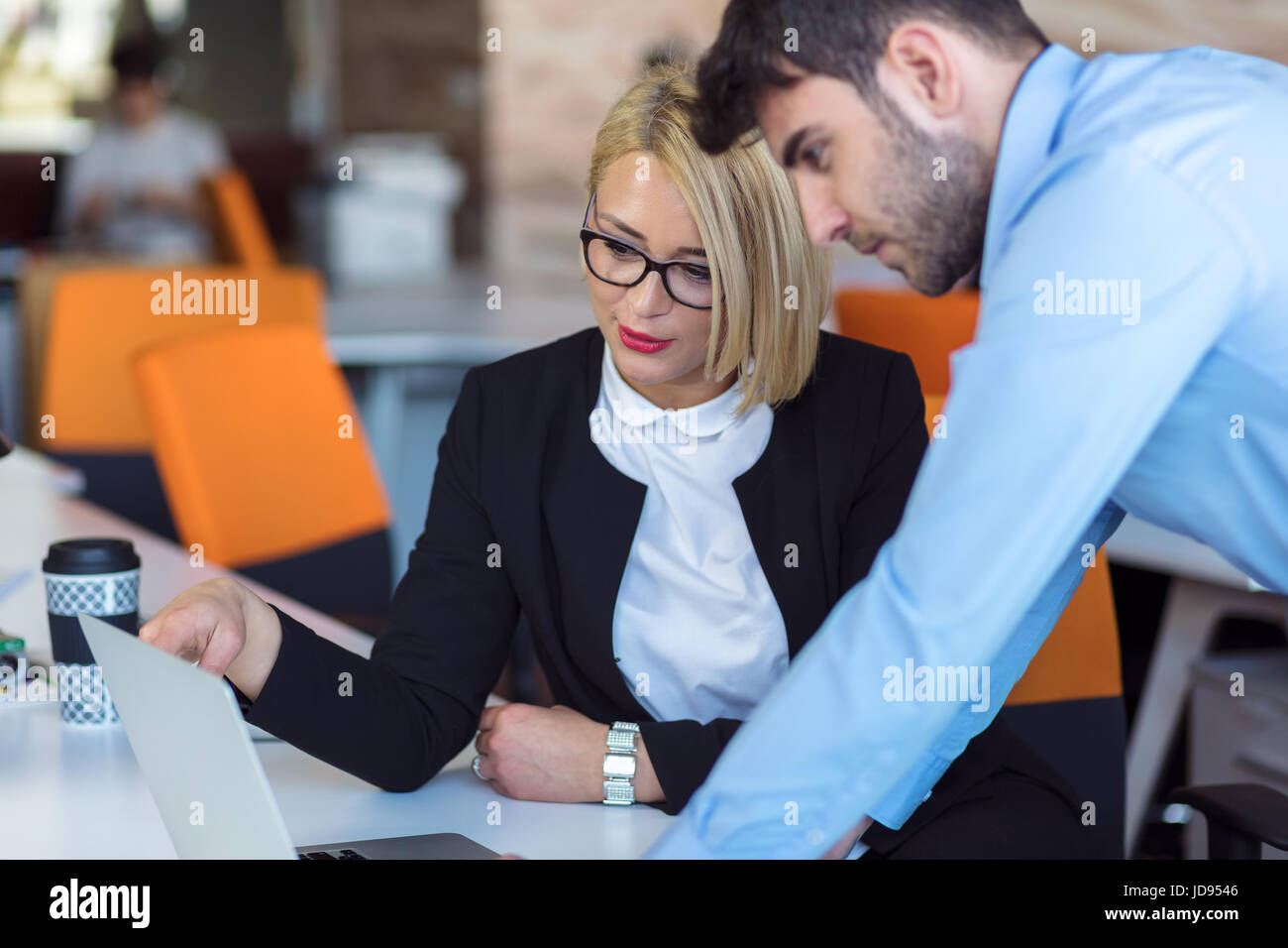 Colleagues chatting, sitting together at office table, smiling Stock ...