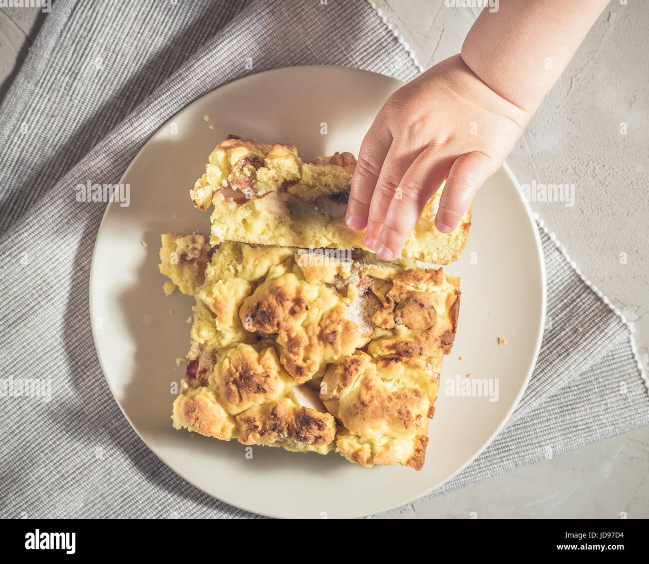 Kid's hand is trying to pick up a piece of pie Stock Photo - Alamy