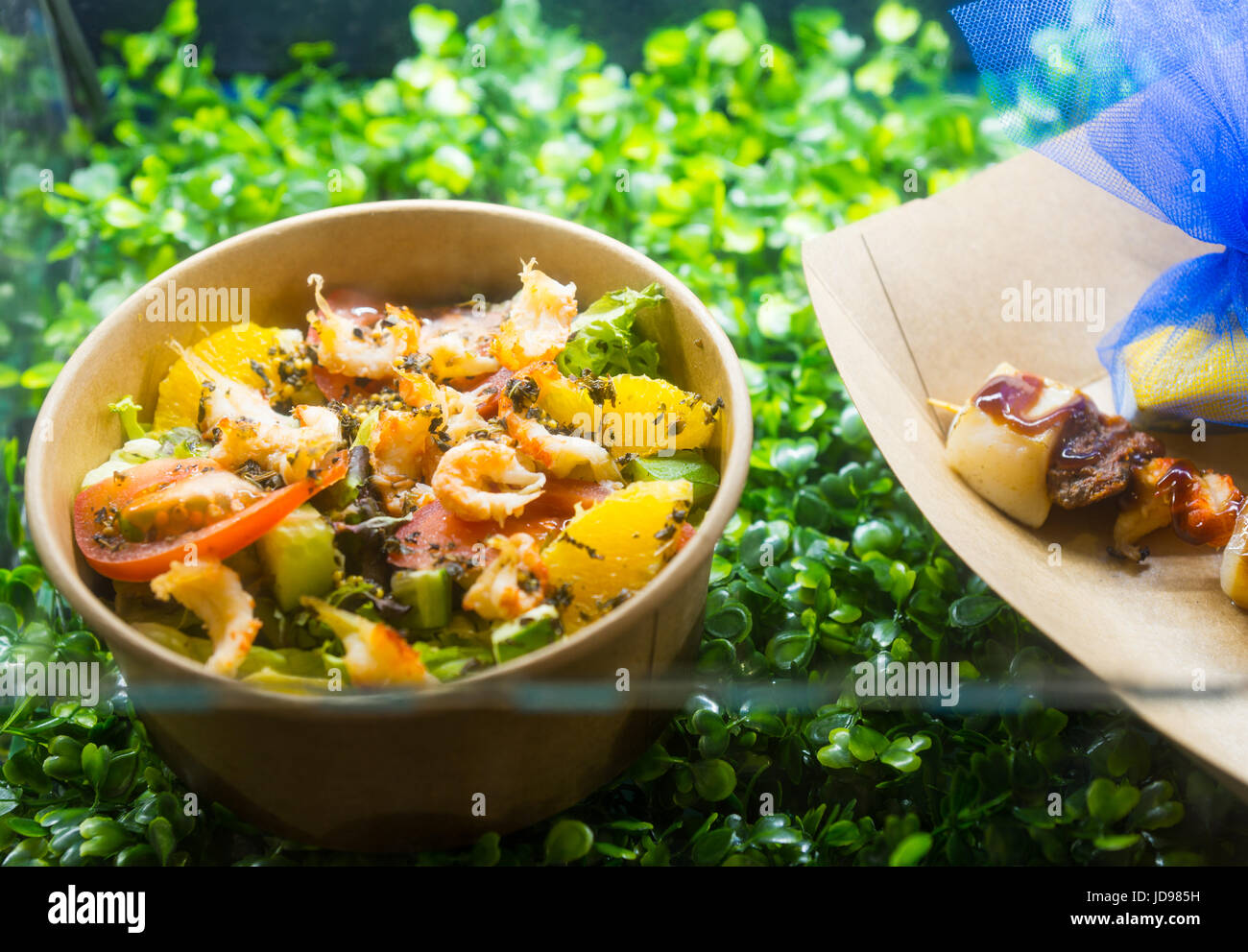 Delicious salad of vegetables and fruits in a cardboard dish on green ...