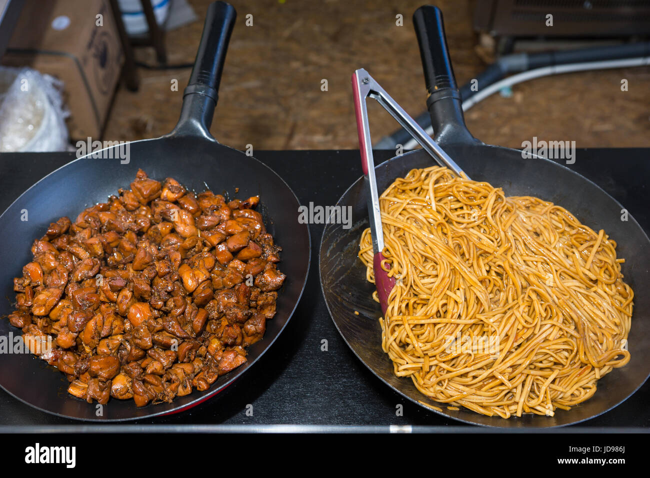 Row of woks with cooked meat and noodles on portable heating devices at ...