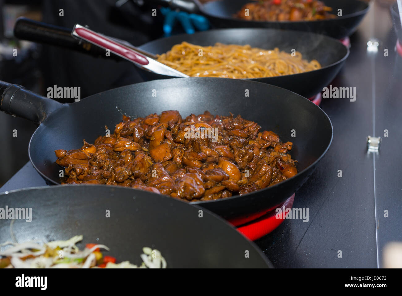 Row of woks with tasty cooked food on portable heating devices at ...