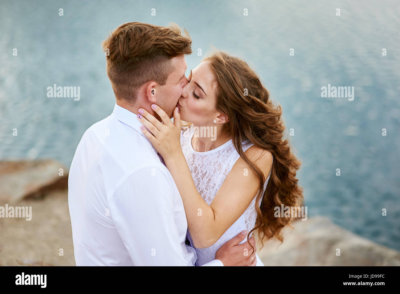 Romantic couple sitting beach kissing hi-res stock photography and ...