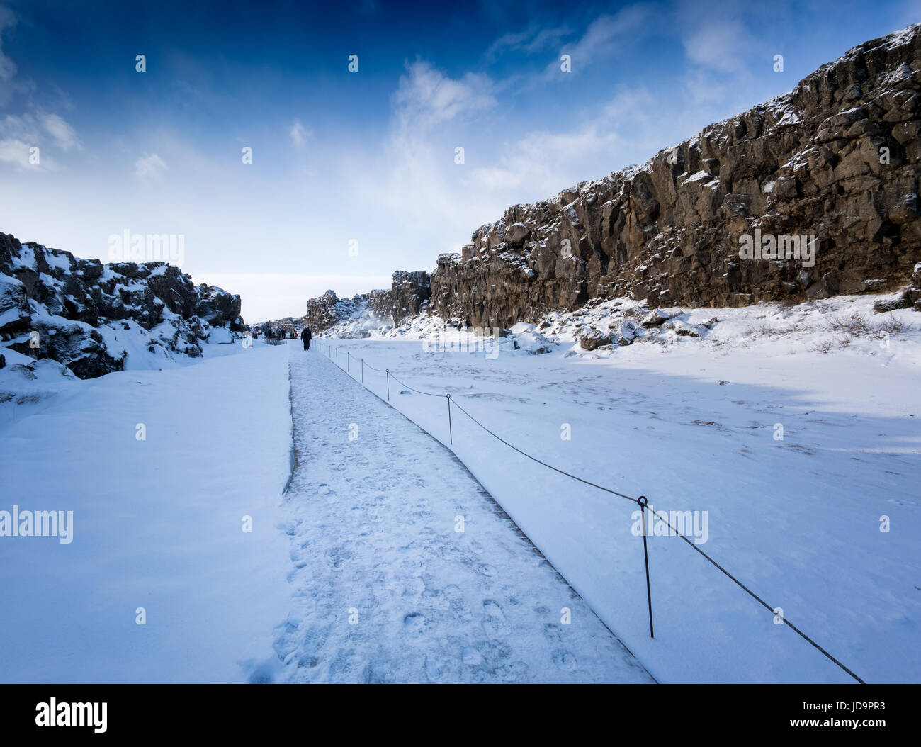 Person walking on snow covered pathway by rock formations, Iceland ...