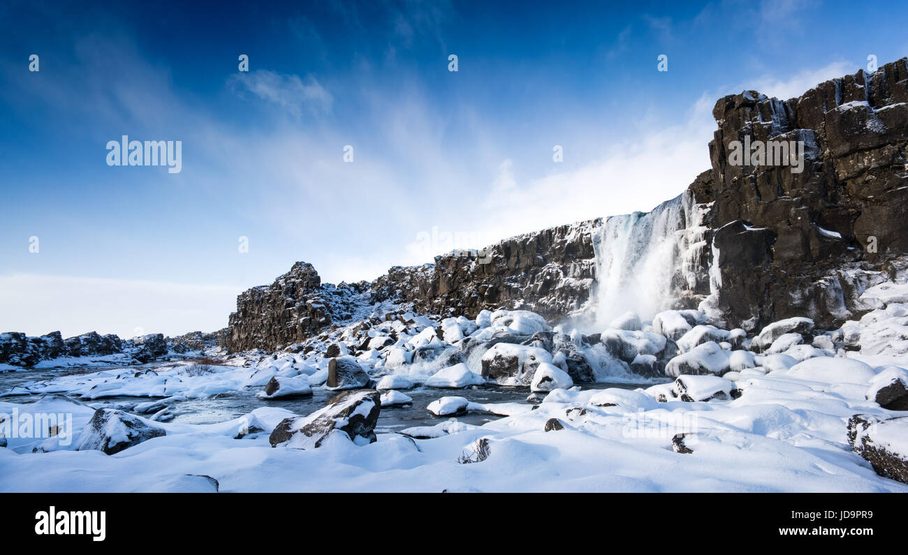 Tourists looking at view of waterfall and cliff face, Iceland, Europe ...