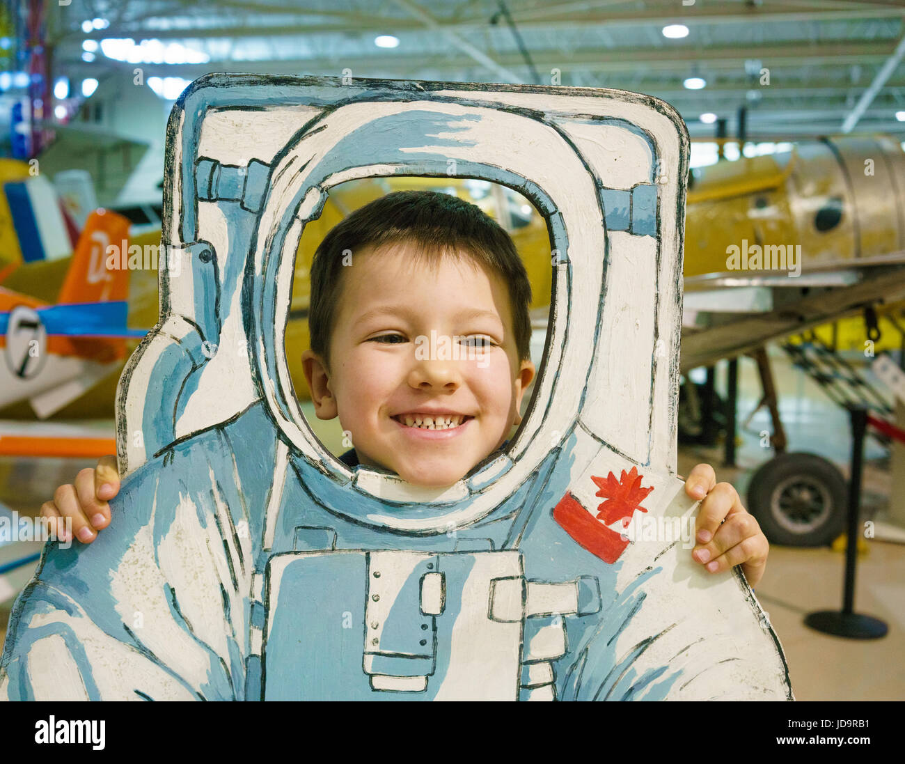 Head shot of young boy smiling with head through astronaut cut out ...