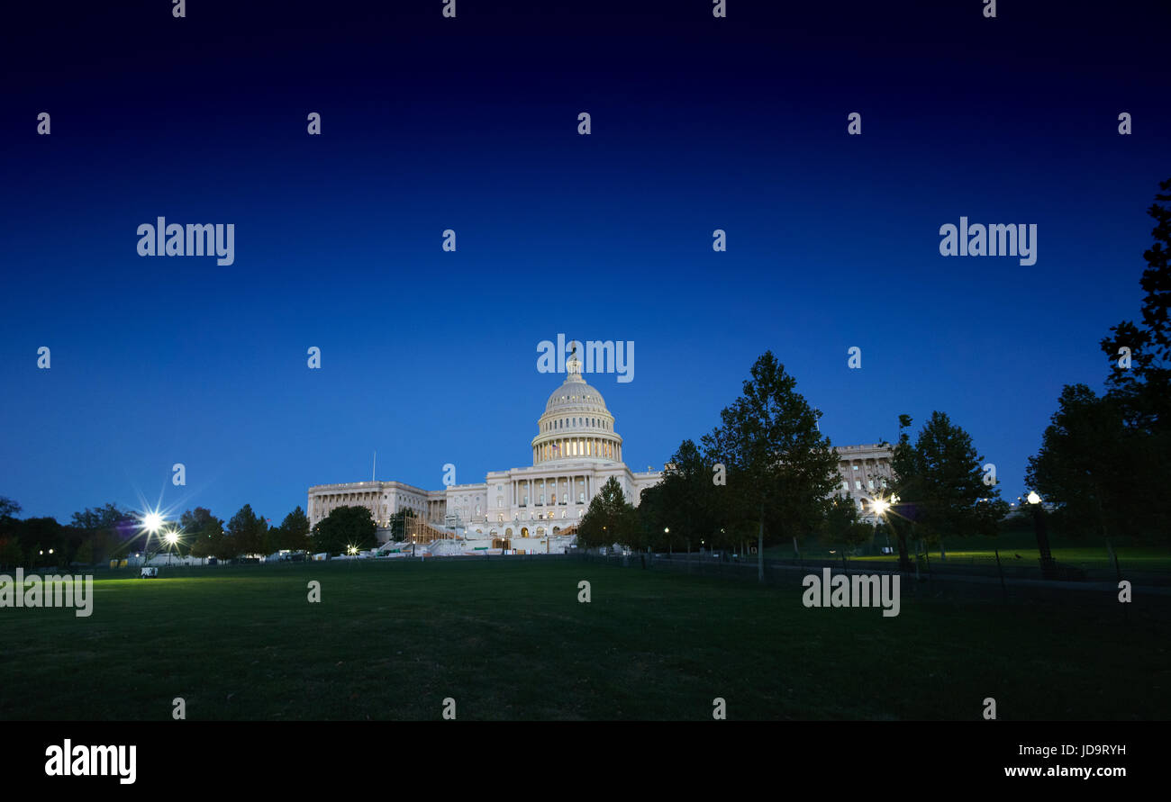 Distant view of Capitol building at dusk and green grass parks ...