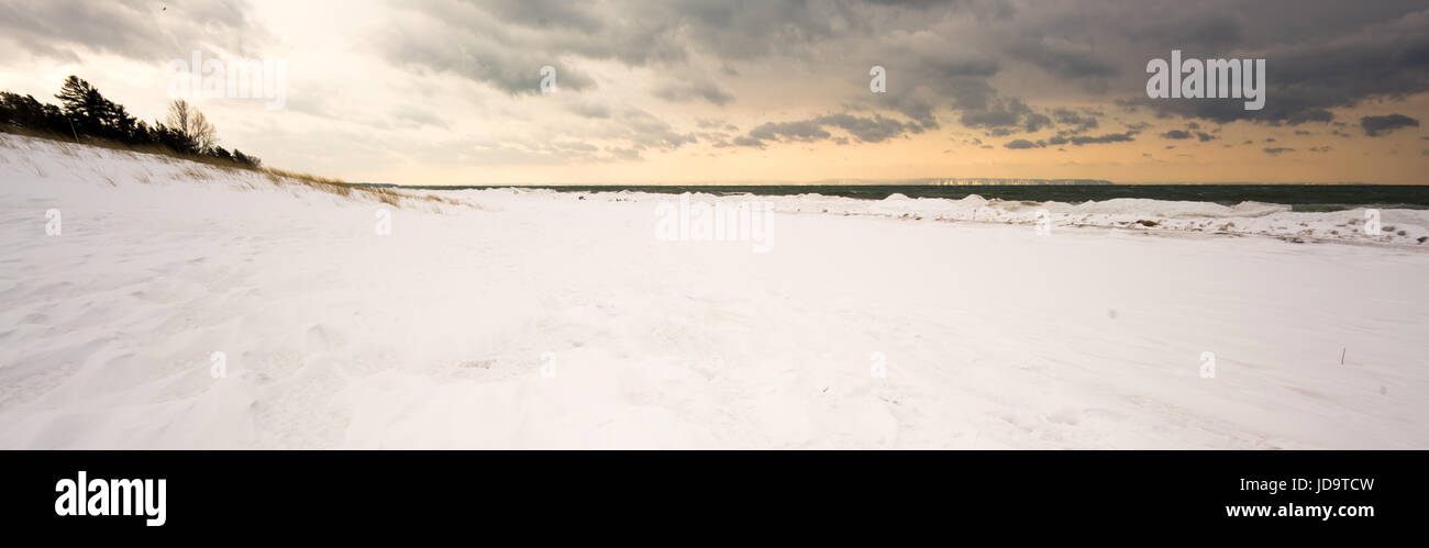 Deserted, snow covered rural landscape near water, dramatic sky ...