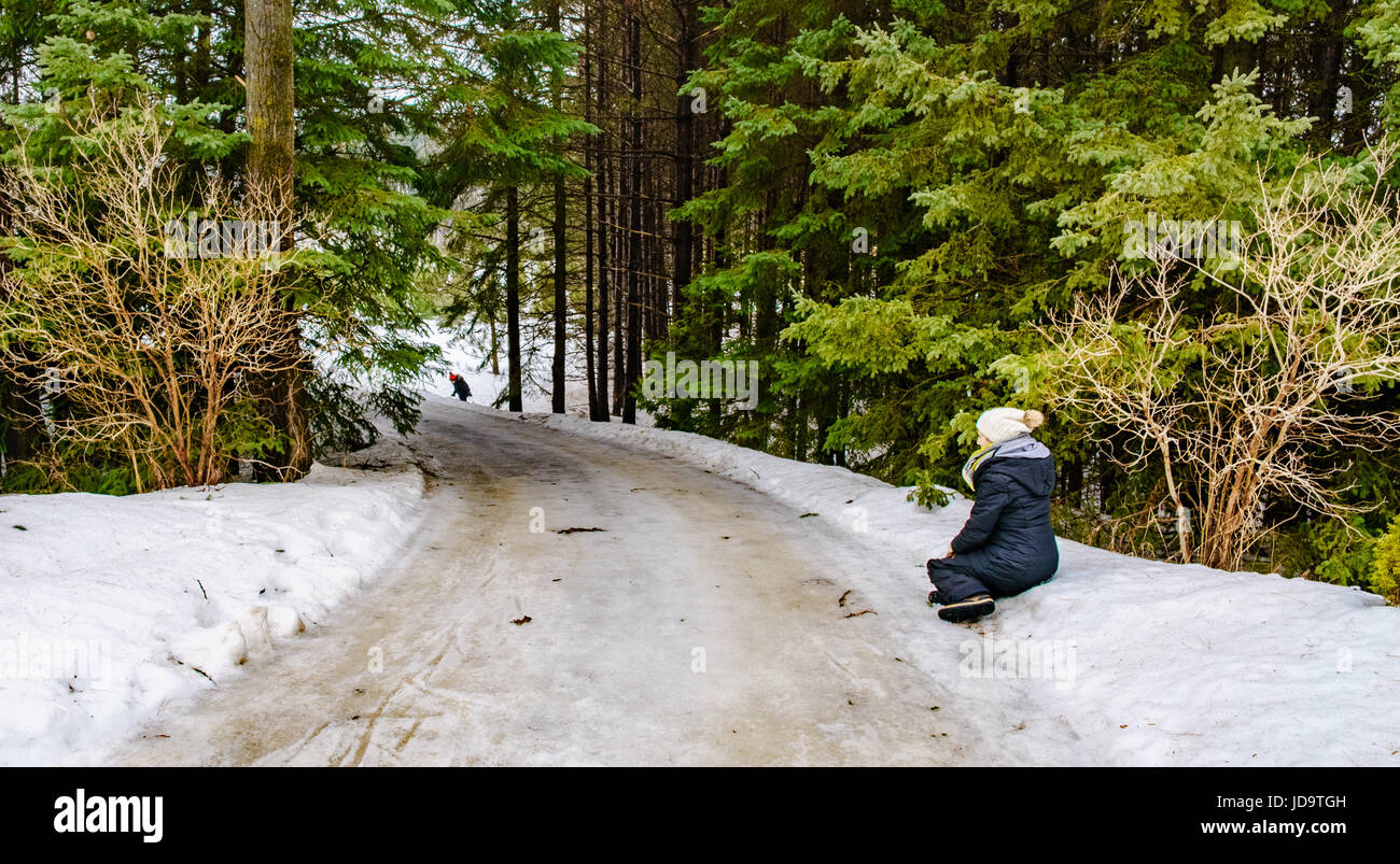 Outdoors, at day with woman sat on side of path in winter, Ontario ...