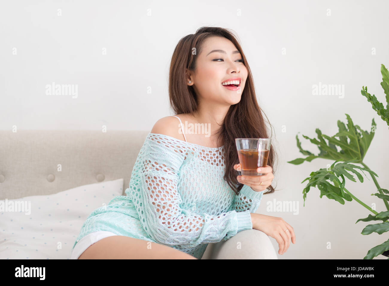 Beautiful young asian woman drinking her morning tea over a breakfast ...