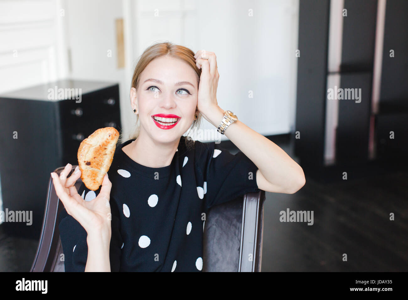 Charming woman eating bun Stock Photo - Alamy