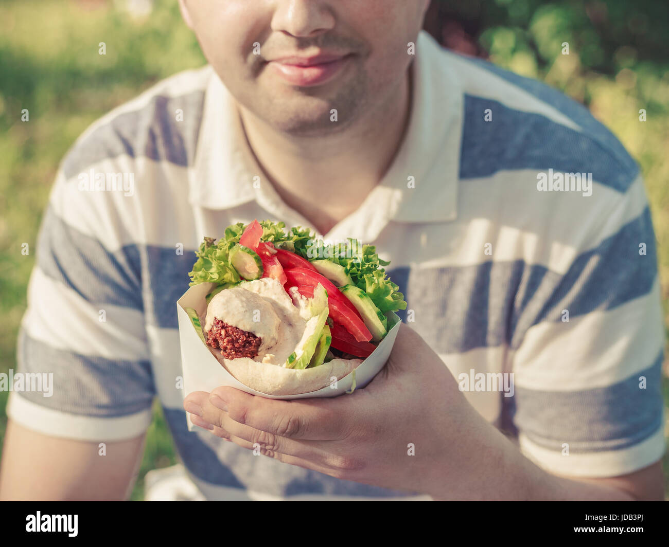 Man is holding falafel sandwich in paper bag. Healthy street food ...