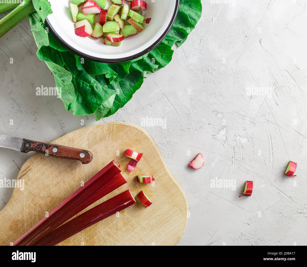 Fresh organic rhubarb stems with cut pieces in metal bowl over grey ...