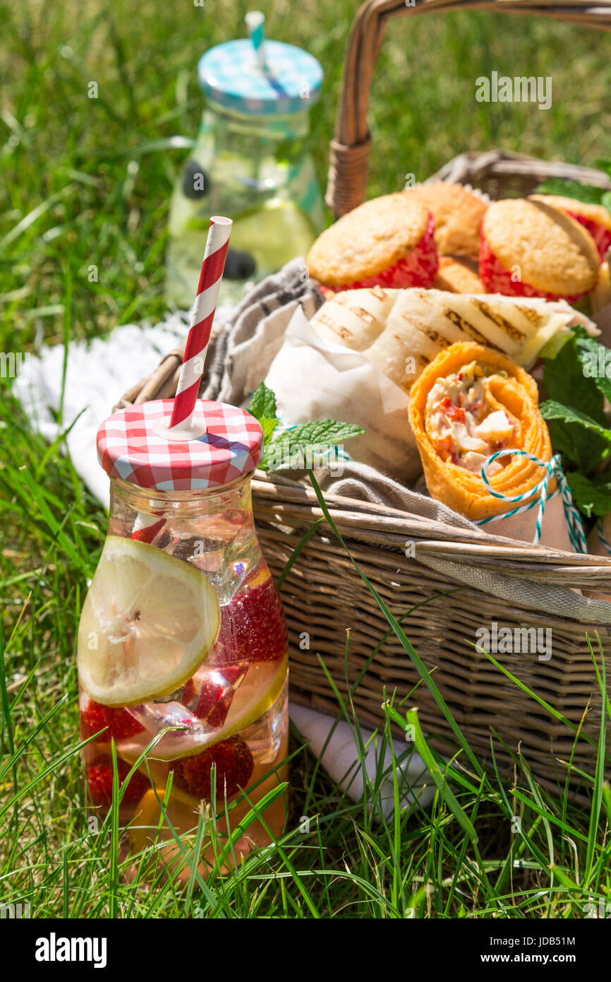 Picnic basket with food on green sunny lawn Stock Photo - Alamy