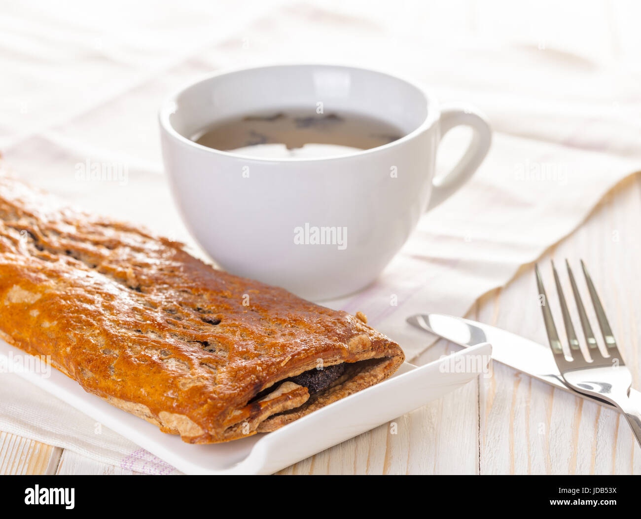 Baking strudel with poppy seeds and tea on a wooden white background ...