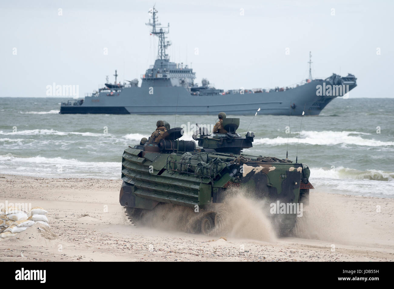 An American Assault Amphibious Vehicle AAV-7 on the beach and Polish minelayer-landing ship ORP ...