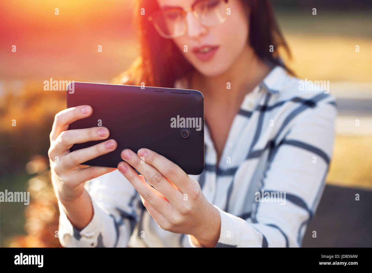 Young woman reading on laptop in park on bench in sunset Stock Photo ...