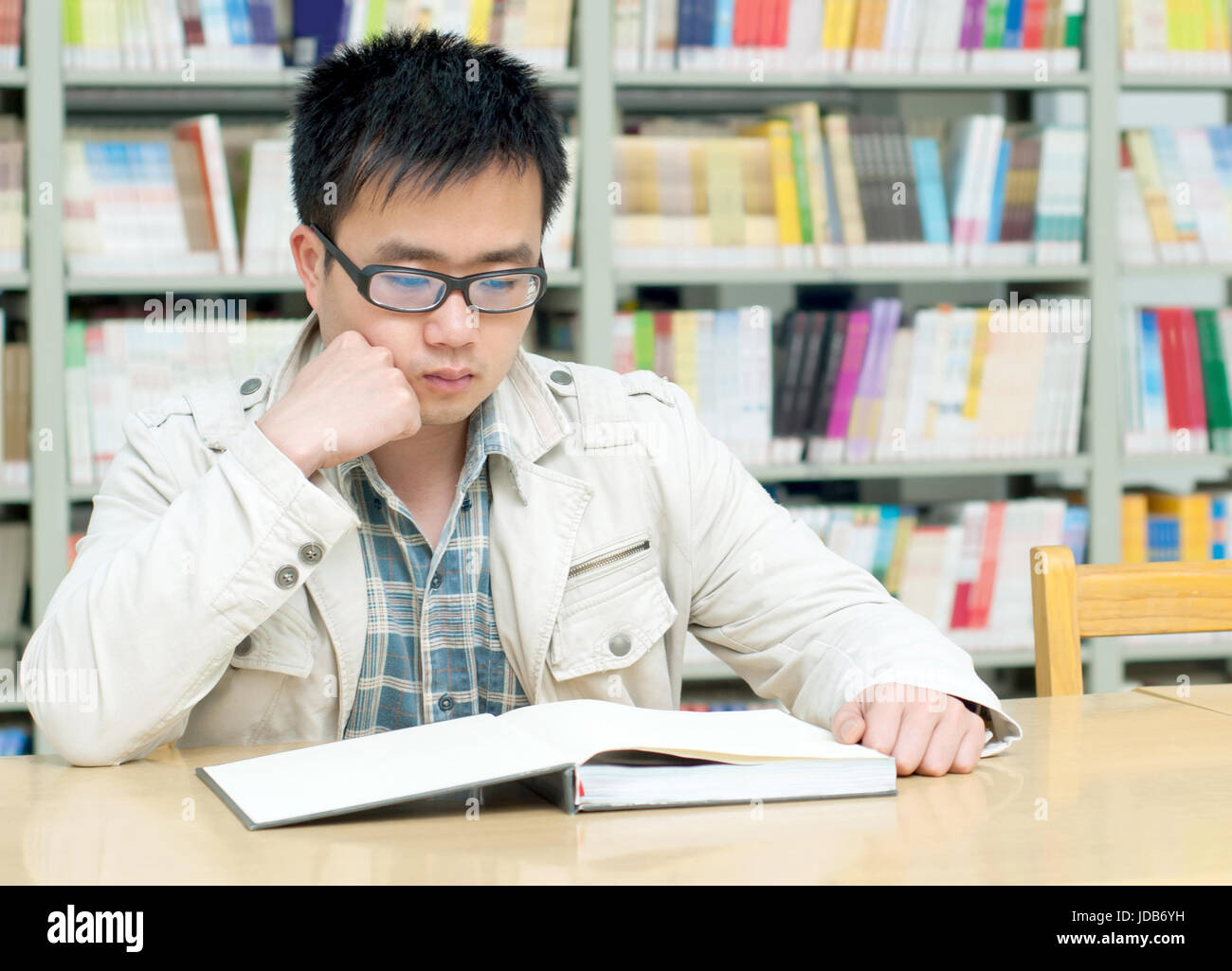 Handsome man sitting and reading in library Stock Photo - Alamy
