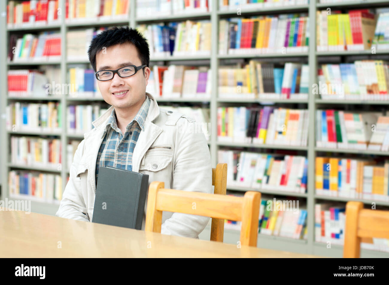 Handsome man sitting and reading in library Stock Photo - Alamy
