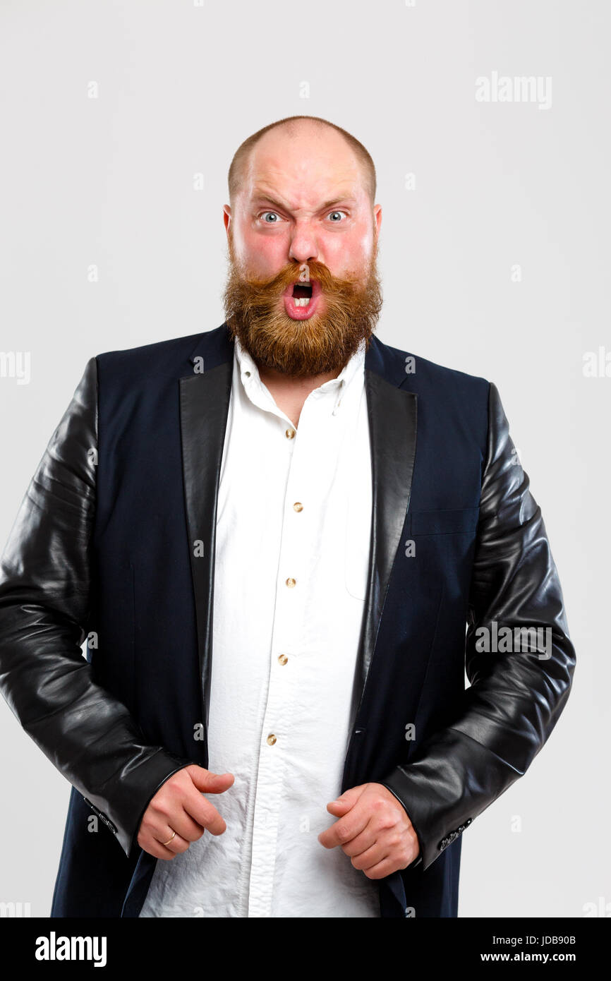 Screaming man with ginger beard in black jacket on empty gray ...